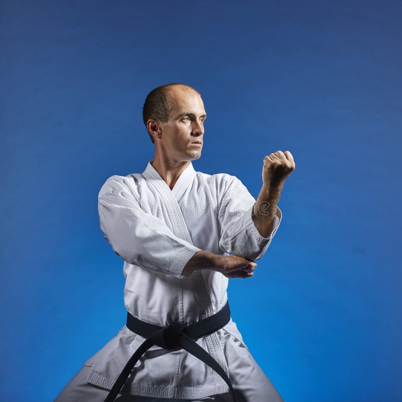 An Athlete Performs Formal Exercises of Karate on a Blue Background ...