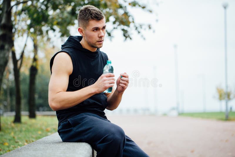 Athlete Resting on Bench in Park after Running with Bottle of Water ...