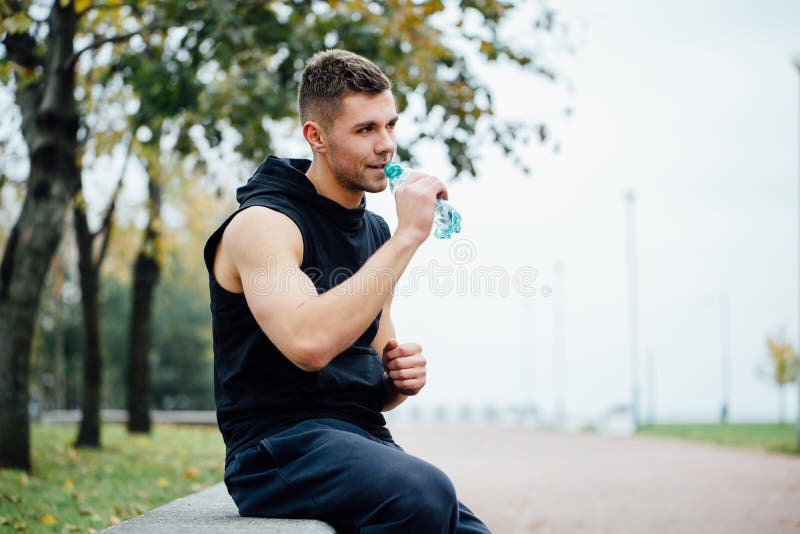 Athlete Resting on Bench in Park after Running with Bottle of Water ...