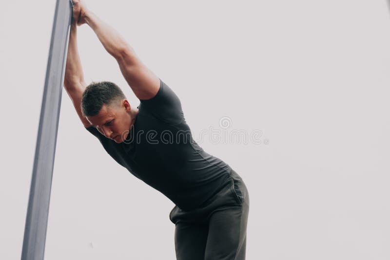 Athlete Young Guy Does a Warm Up on the Simulator. Stretching Back ...