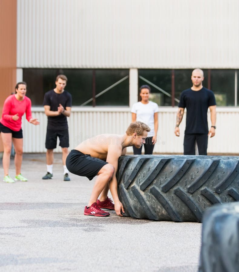 Athletes Motivating Friend in Flipping Tire Stock Image - Image of ...