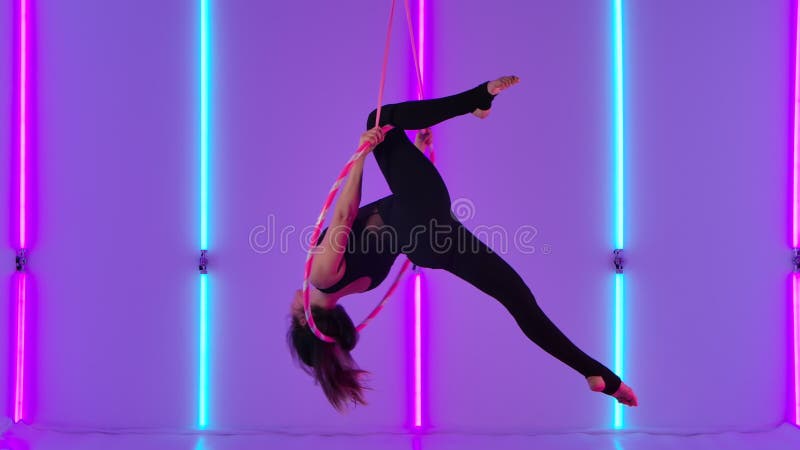 An Athletic Aerial Girl Acrobat in a Black Leotard Performs at a Height ...