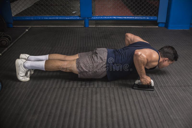 An Athletic Man Does Pushups with Push-up Handle Bars on the Rubber ...