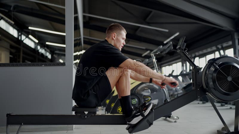 Athletic Man Focused while Training on Rowing Machine in Gym Stock ...