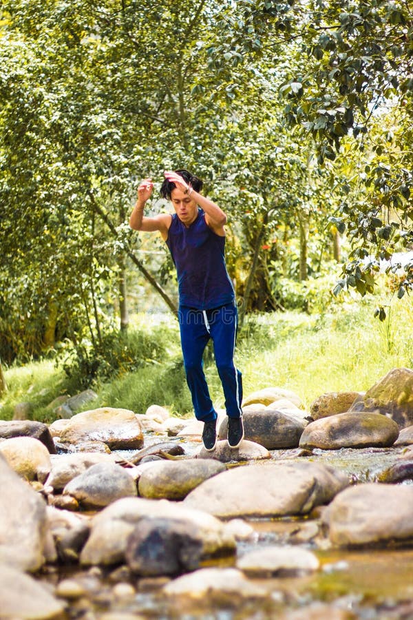 Athletic Man Jumping on the Rocks in the River Stock Photo - Image of ...