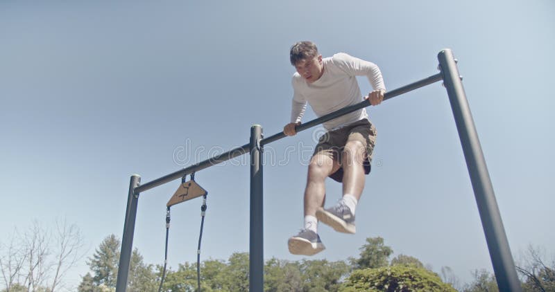 Athletic Man Performing Pull Ups Exercises on Parallel Bars in an ...