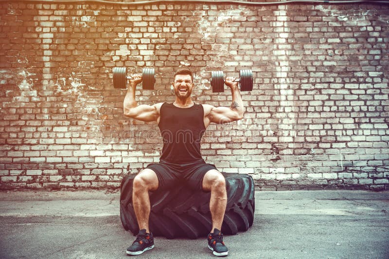 Muscular Guy Doing Exercises with Dumbbell Against a Brick Wall Stock ...