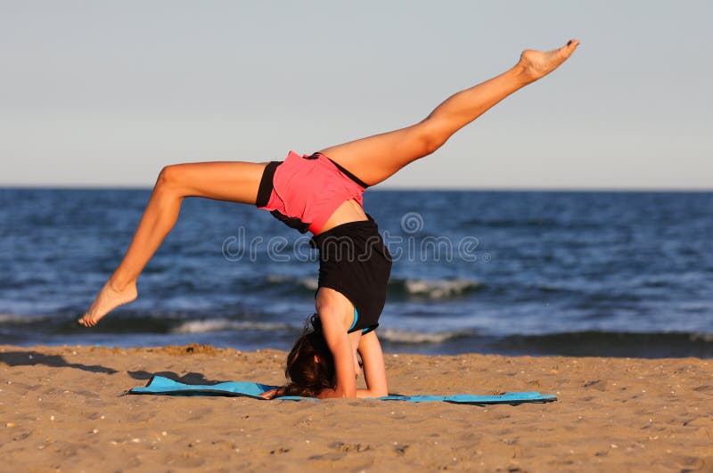 Athletic Slender Girl by the Sea Does Gymnastic Training with Head Down ...