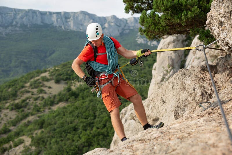Athletically Built Man Climbs a Rock Using a Rope. Stock Photo - Image ...