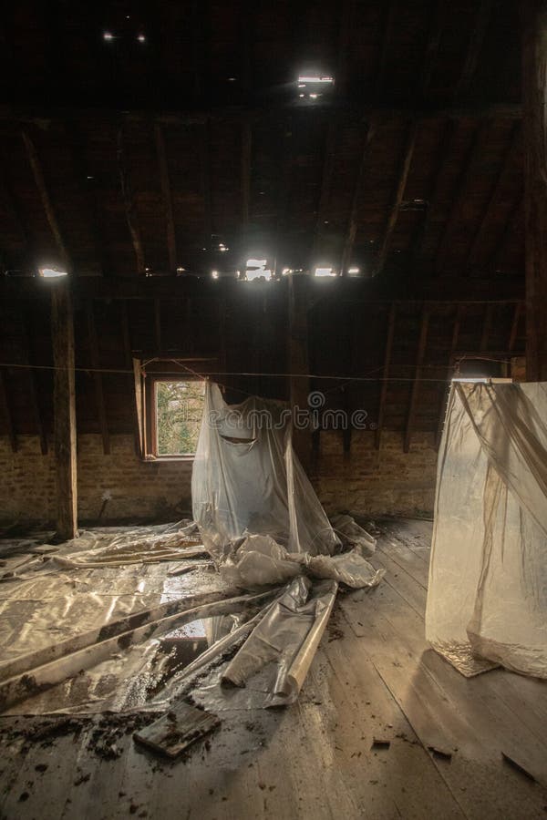 Abandoned Attic with Torn Plastic Sheets and Sunlight through Cracks ...