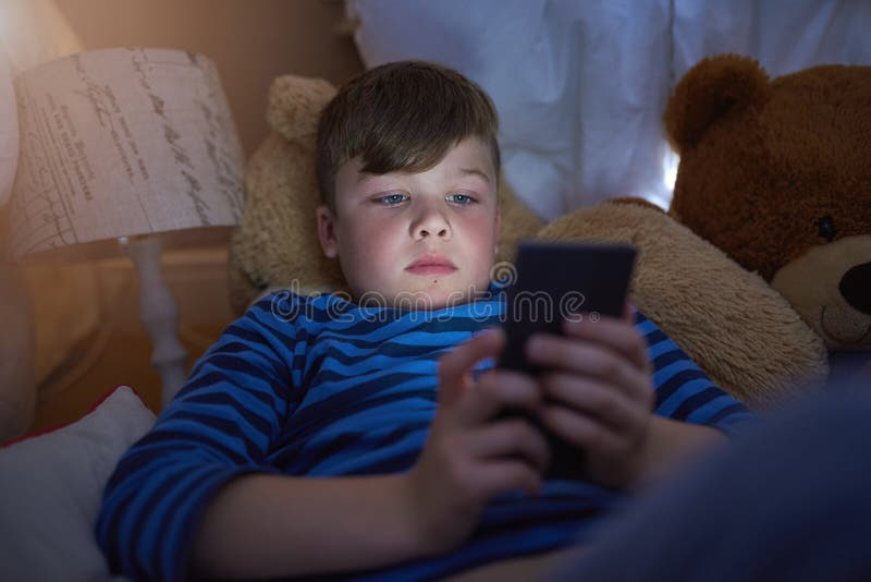Attached To Technology. a Young Boy Using a Cellphone at Night in Bed ...