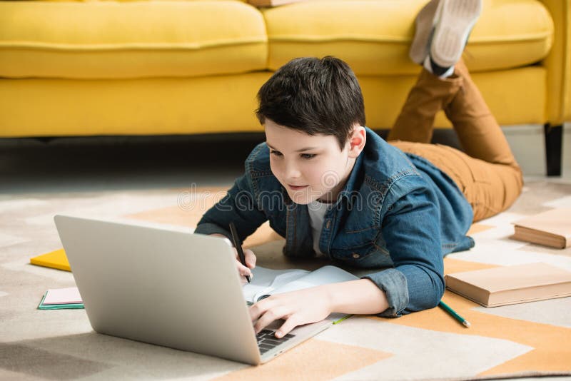Boy Lying on Floor Near Books and Using Laptop while Doing Homework ...