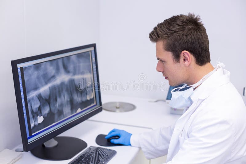 Attentive Dentist Examining X-ray Report on Computer Stock Image ...