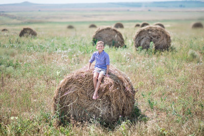 Attractive Boy Sitting on a Haystack and Smiling Stock Photo - Image of ...