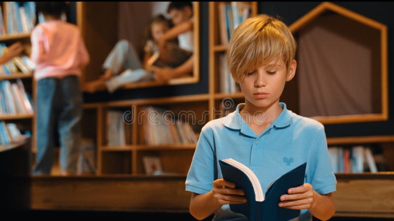 Attractive Boy Reading Book while Group of Students Learning Behind ...