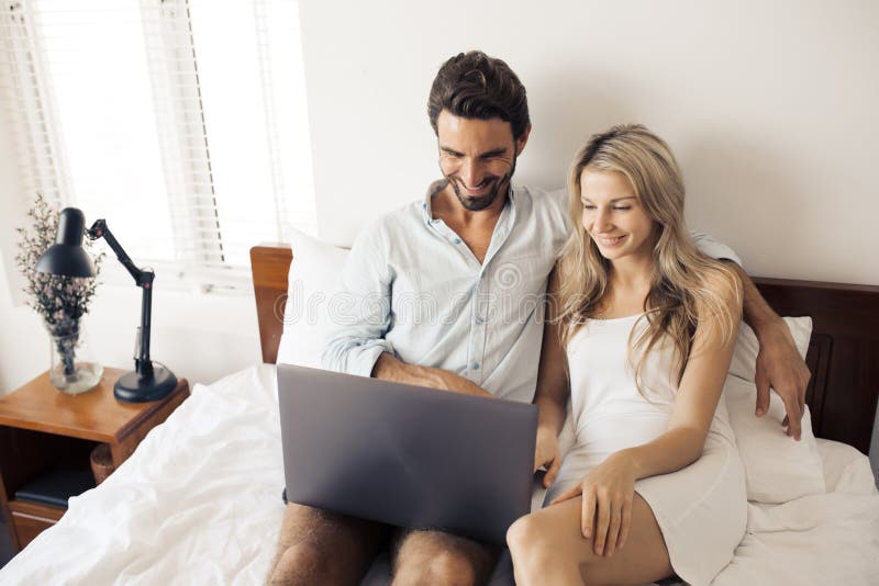 Attractive Couple Using Laptop in Bedroom. Stock Photo - Image of ...