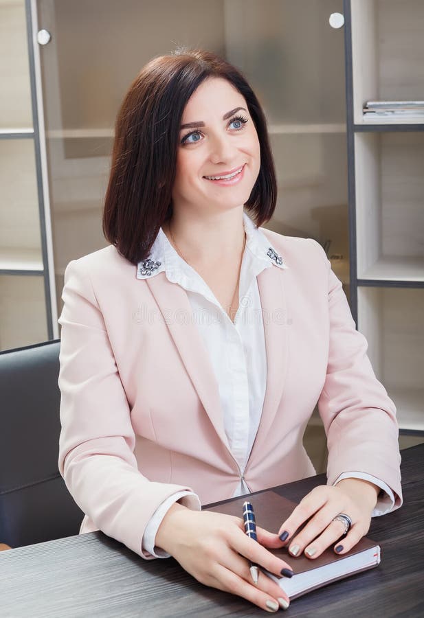 Attractive Dark Haired Woman Wearing A Black And White Blouse Sitting