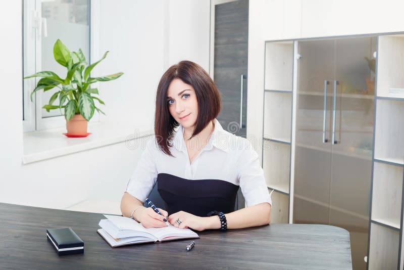 Attractive Dark Haired Woman Wearing A Black And White Blouse Sitting