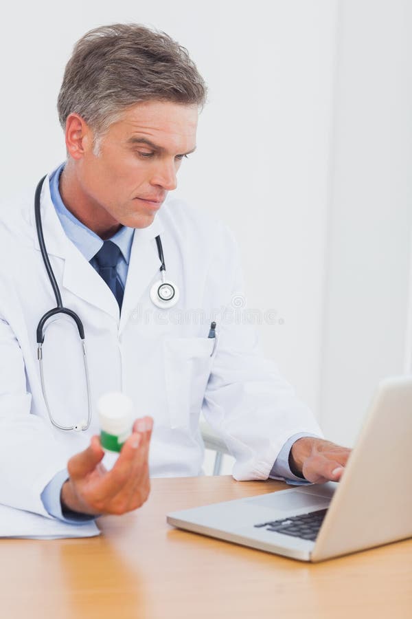 Doctor in Scrubs Using Computer at Hospital Desk Stock Image - Image of ...