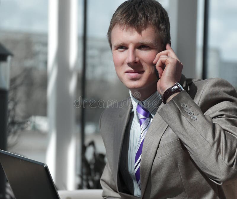 Attractive European Guy Talking on Phone while Using Laptop. Stock ...