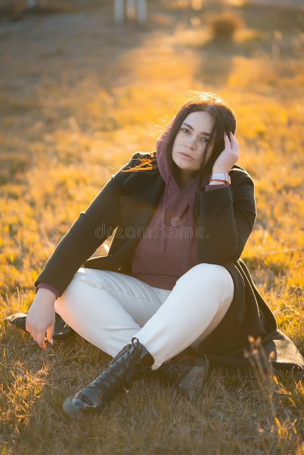 Attractive Girl Sitting on the Grass in the Park and Looking Alone at ...