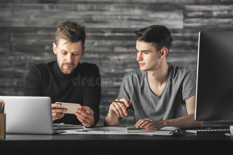 Attractive Guys Using Smartphone at Workplace Stock Photo - Image of ...