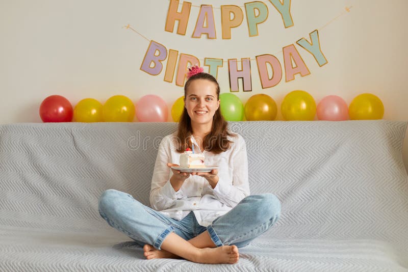 Attractive Happy Girl Sitting On The Sofa And Blows Out Burning Candle
