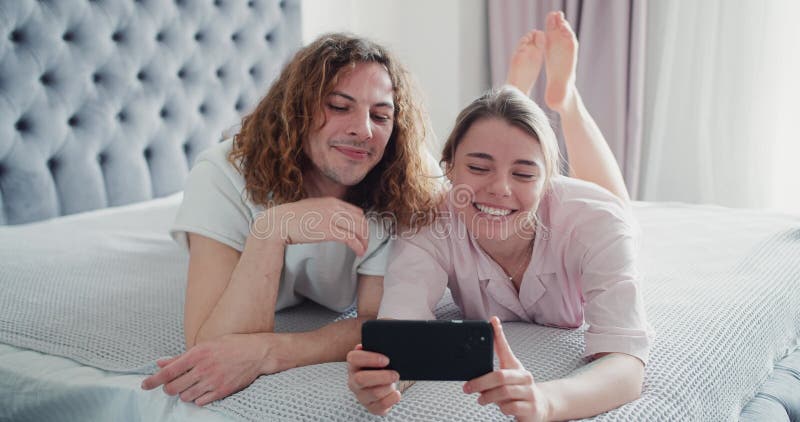 Attractive Happy Young Couple Laying On Bed In The Bedroom Making