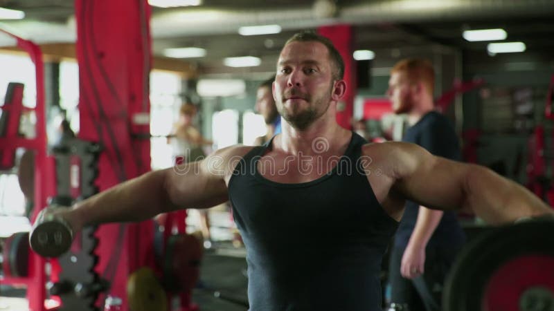 An Attractive Man Bodybuilder Performing Side Raise Exercise with ...
