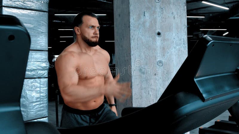 An Attractive Man Bodybuilder Running on the Treadmill and Changing ...