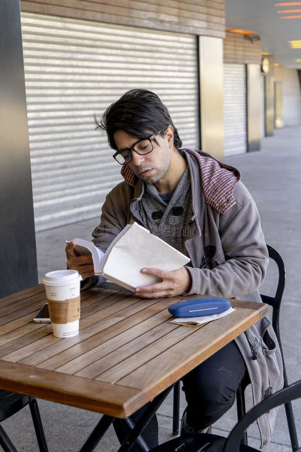 Attractive Man Sitting in a Bar Drinking Coffee while Reading a Book ...