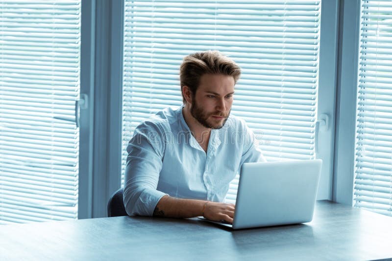 Attractive Man Sitting Working at a Laptop Stock Image - Image of ...