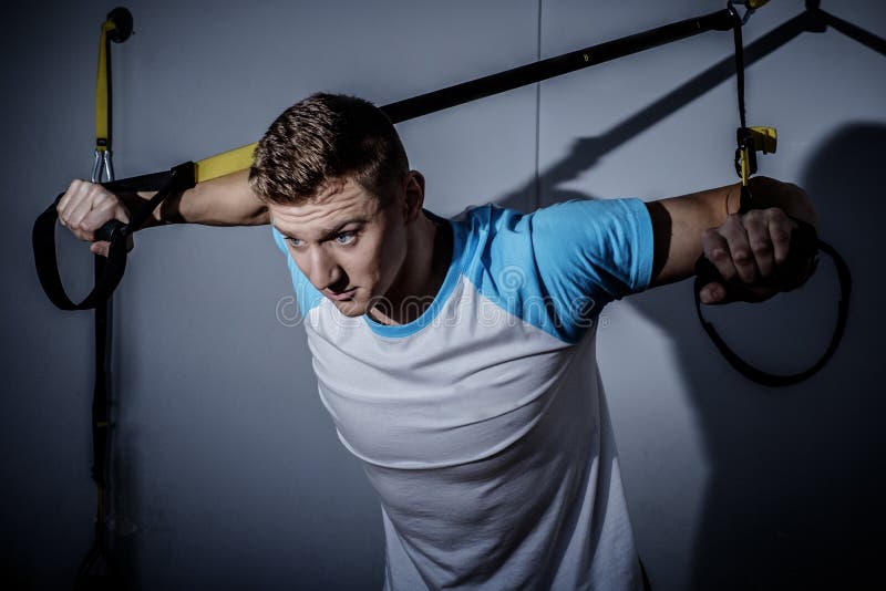 Attractive Man during Workout with Suspension Straps in the Gym Stock ...