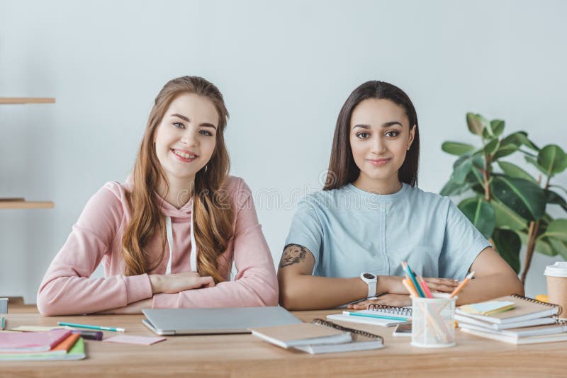 Attractive Multiethnic Students Sitting at Table with Books and Laptop ...