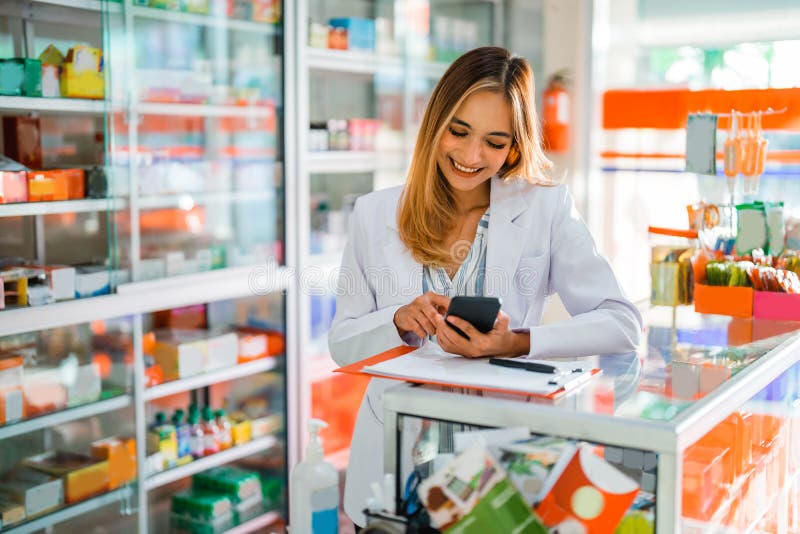 Attractive Pharmacist in Uniform Using Smartphone while Working Stock ...