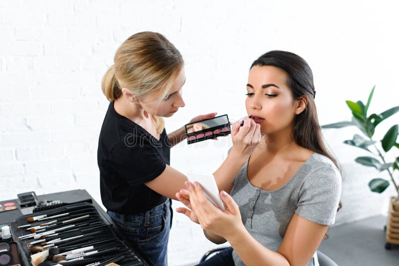 Attractive Woman Using Smartphone while Makeup Artist Stock Photo ...