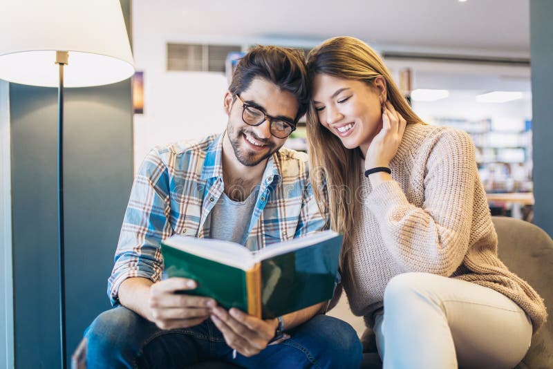 Young Couple in a Library Reading a Book Together Stock Photo - Image ...