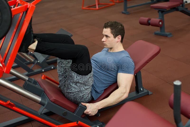 Attractive Young Man Doing Leg Press on Machine in Gym. Stock Image ...