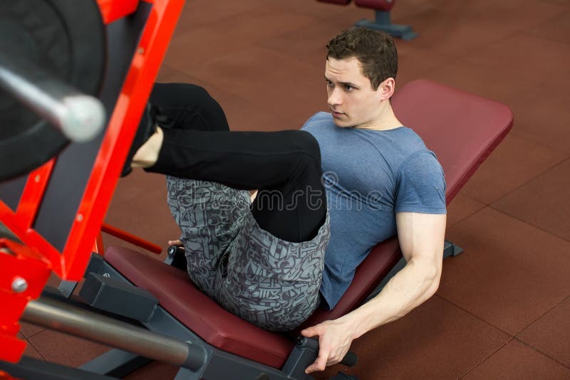 Attractive Young Man Doing Leg Press on Machine in Gym. Stock Image ...