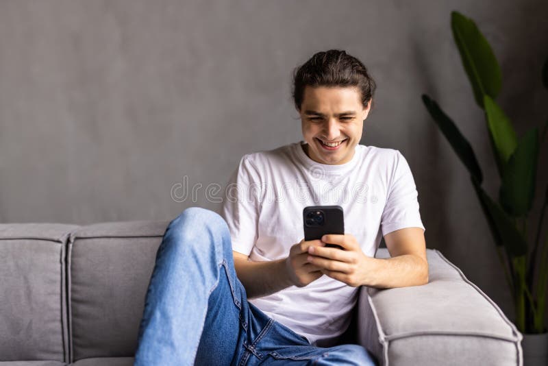 Attractive Young Man Sitting on a Floor in the Living Room, Using ...