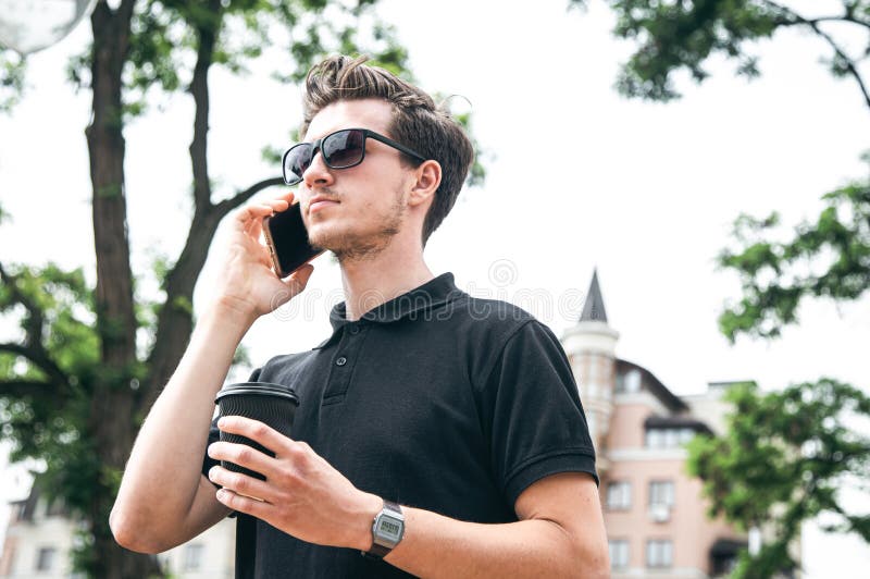 Attractive Young Man in Sunglasses Talking on a Smartphone in the City ...