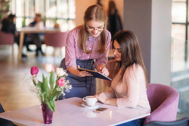 Attractive Young Waitress Using a Tablet Computer To Take an Order from ...