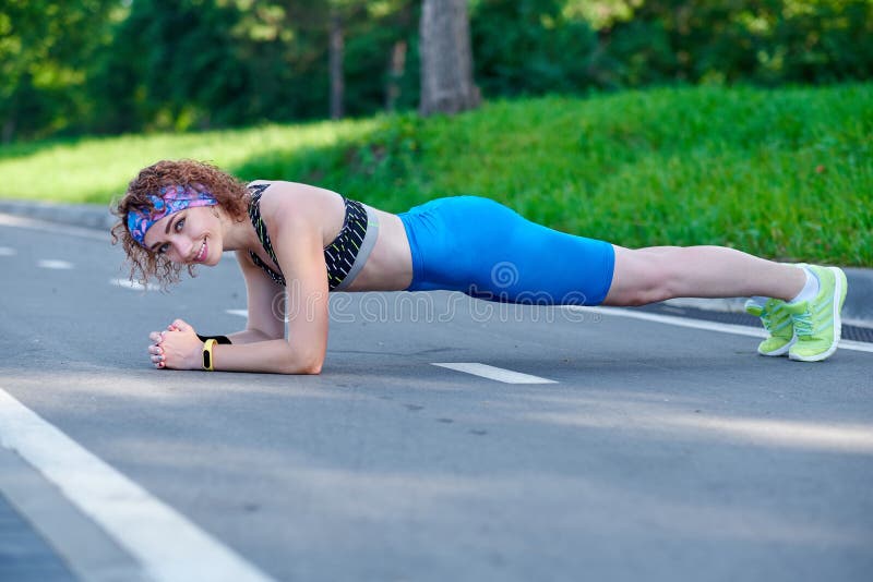 Attractive Young Woman Athlete Doing Plank Exercise On Racetrack Stock
