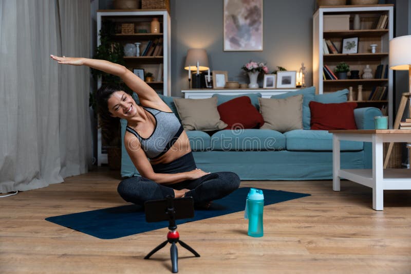 Attractive Young Woman Learning New Exercises Watching Online Workout Tutorials Over Her Phone ...