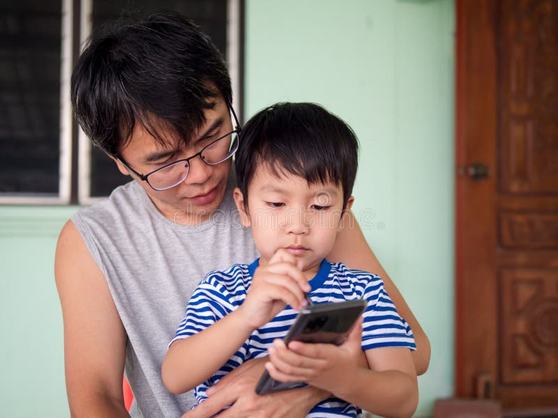 Authentic Asian Child Boy and Father Watching To Mobile Phone Together ... Authentic Asian Child Boy and Father Watching To Mobile Phone Together ...