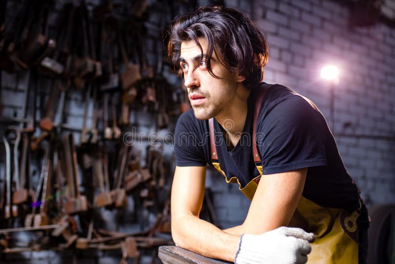 Authentic Blacksmith Man Forges a Metal Product in Dark Indoors Studio ...