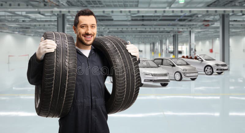Auto Mechanic Carrying Two Car Tires in a Garage Stock Image - Image of ...