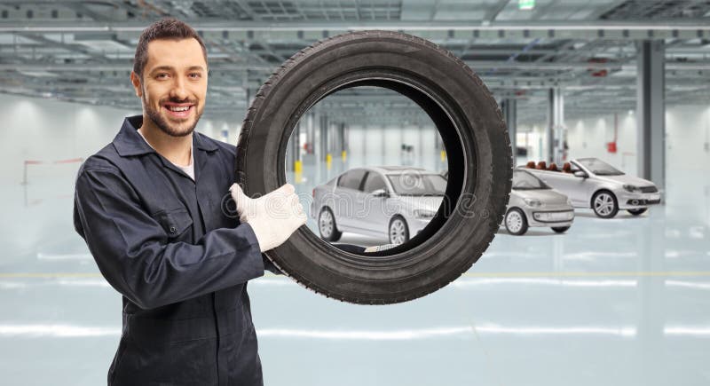Auto Mechanic Holding a Car Tire and Smiling at Camera in a Garage ...