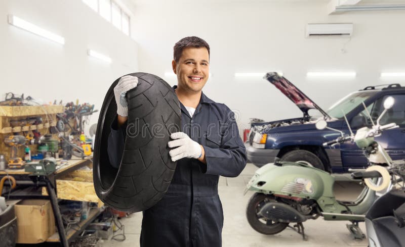 Auto Mechanic Holding a Tire in a Car Garage Stock Photo - Image of ...