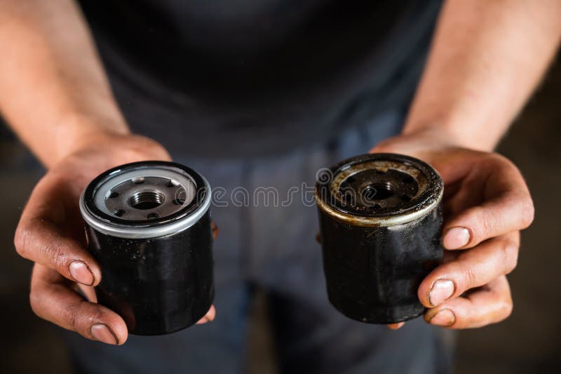 An Auto Mechanic Holds a New and Used Oil Filter. Stock Image - Image ...